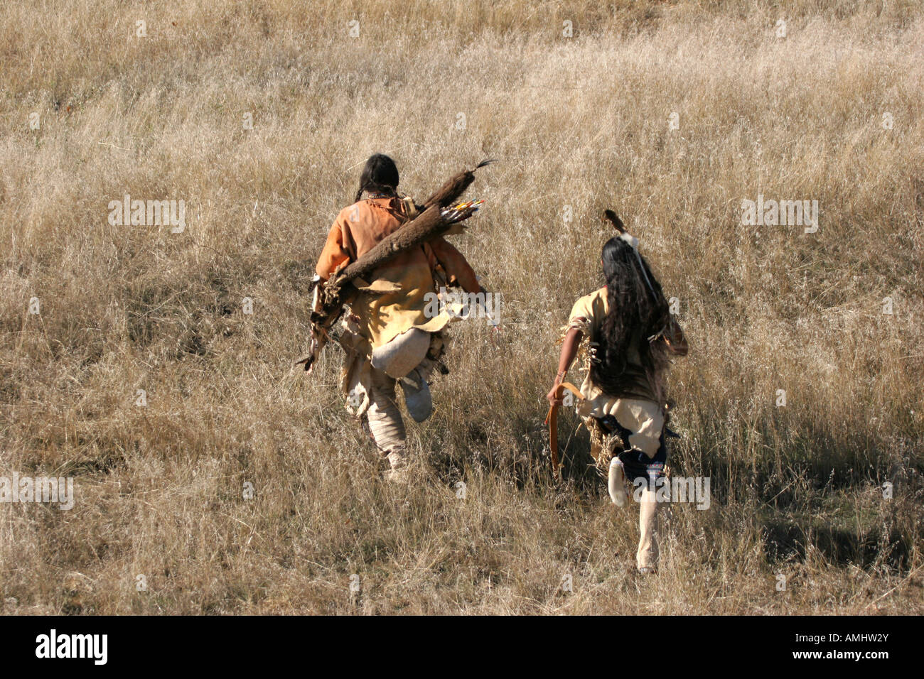 Two Native American Indian men running uphill in the dry grasses of ...