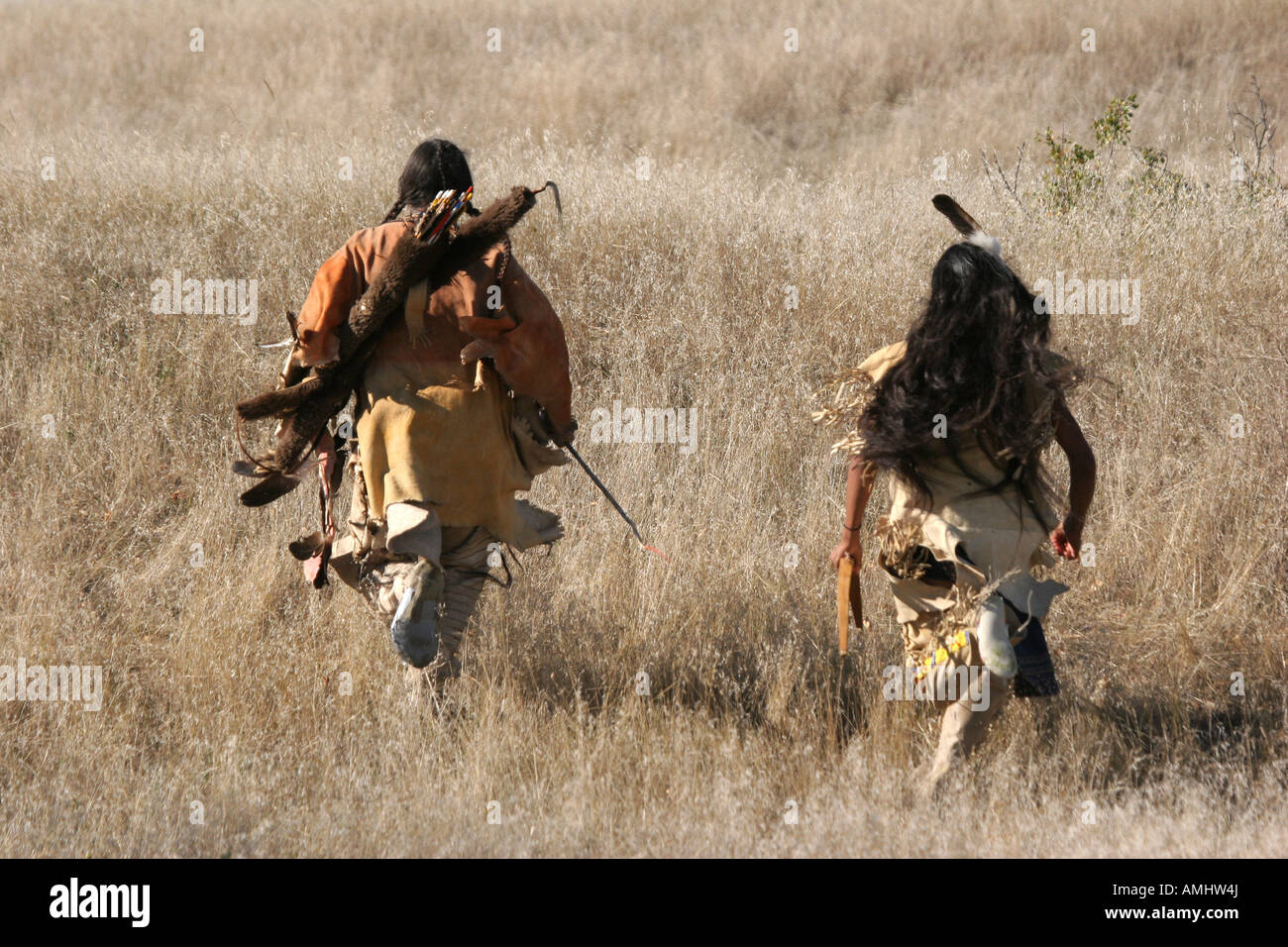 Two Native American Indian men running uphill in the dry grasses of ...
