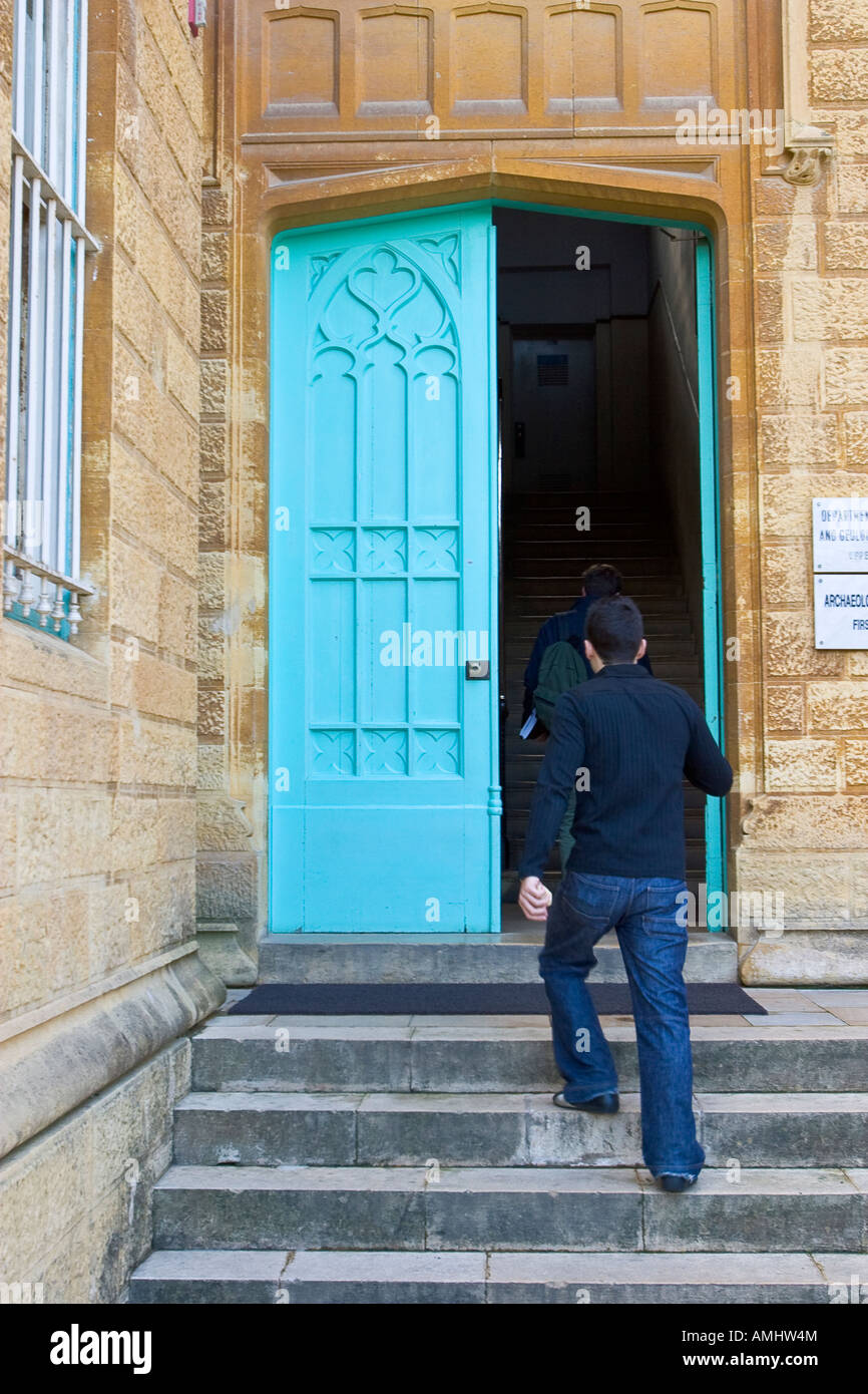Students entering through a blue green colored door to a building at ...