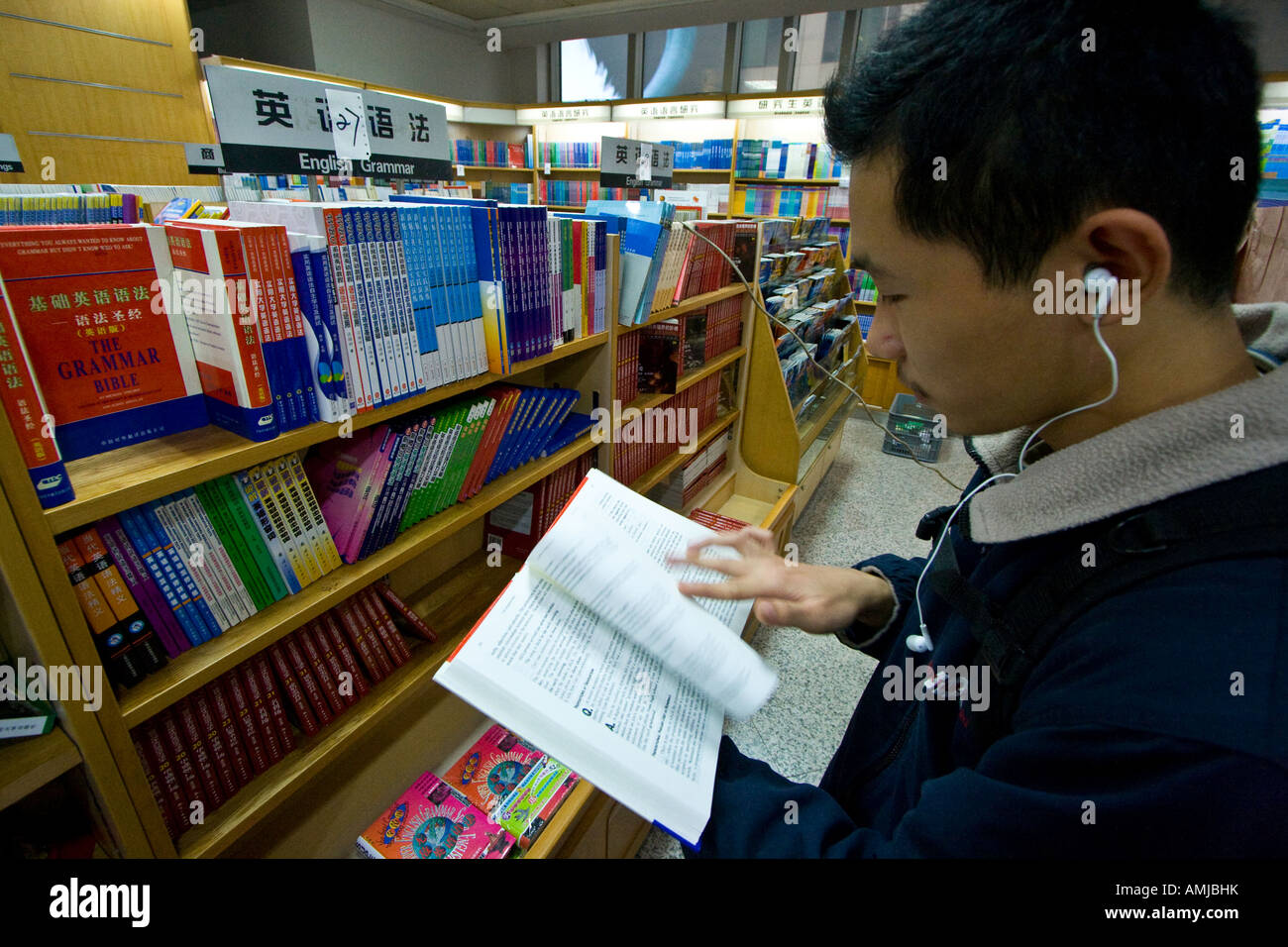 Young Chinese Man with Headphones Reading an English Language Young ...