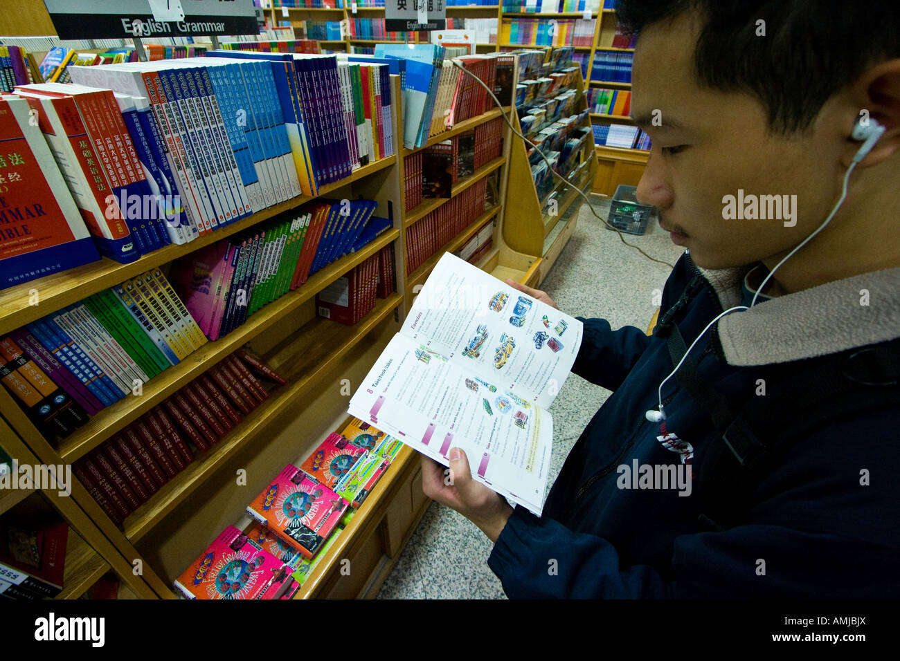 Young Chinese Man with Headphones Reading an English Language Book ...