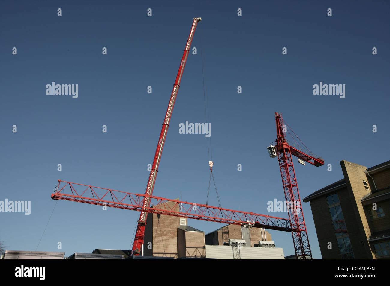 Workmen putting up a tower crane on a builing site to move objects ...