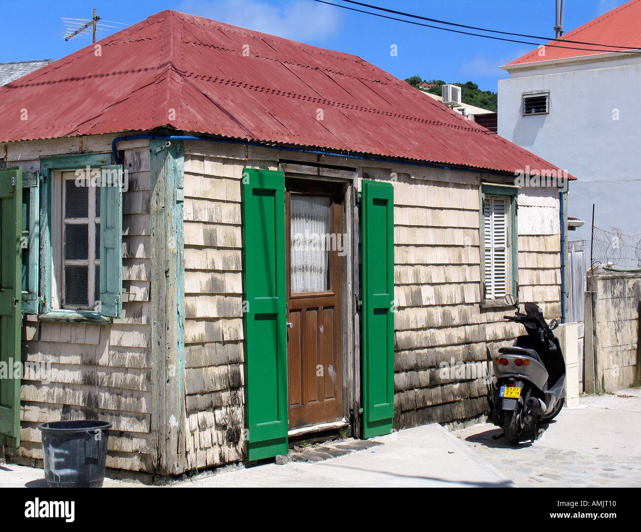 Traditional wooden shingle house with red tin roof and blue and green ...
