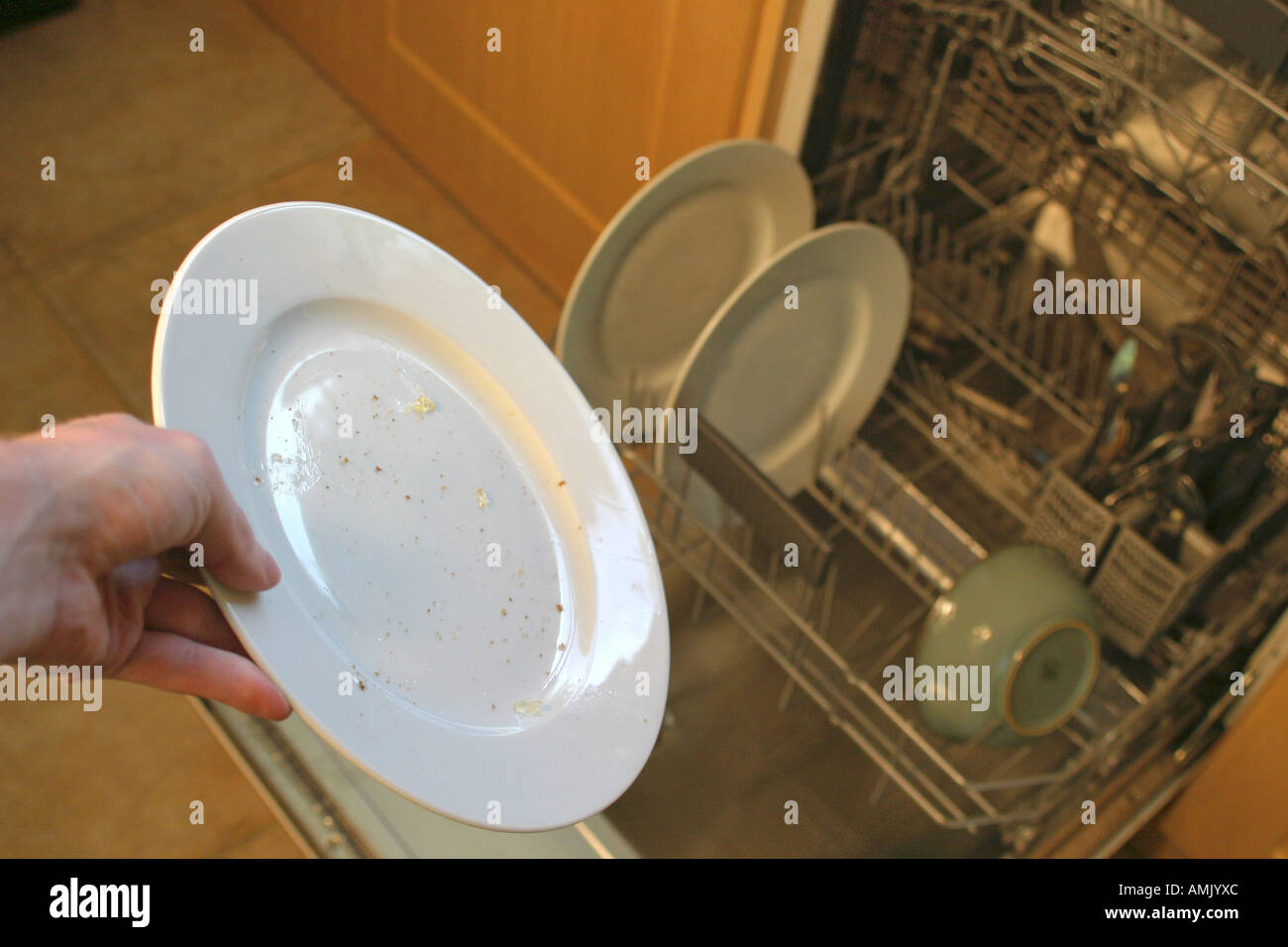 a man placing a dirty plate in a dishwasher Stock Photo - Alamy