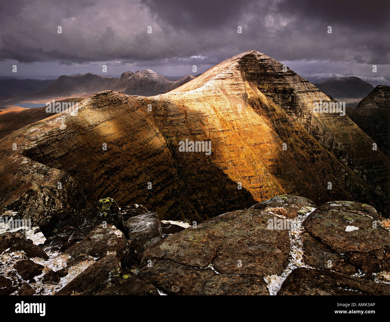 Transient light breaks through heavy grey cloud and paints the summit ...