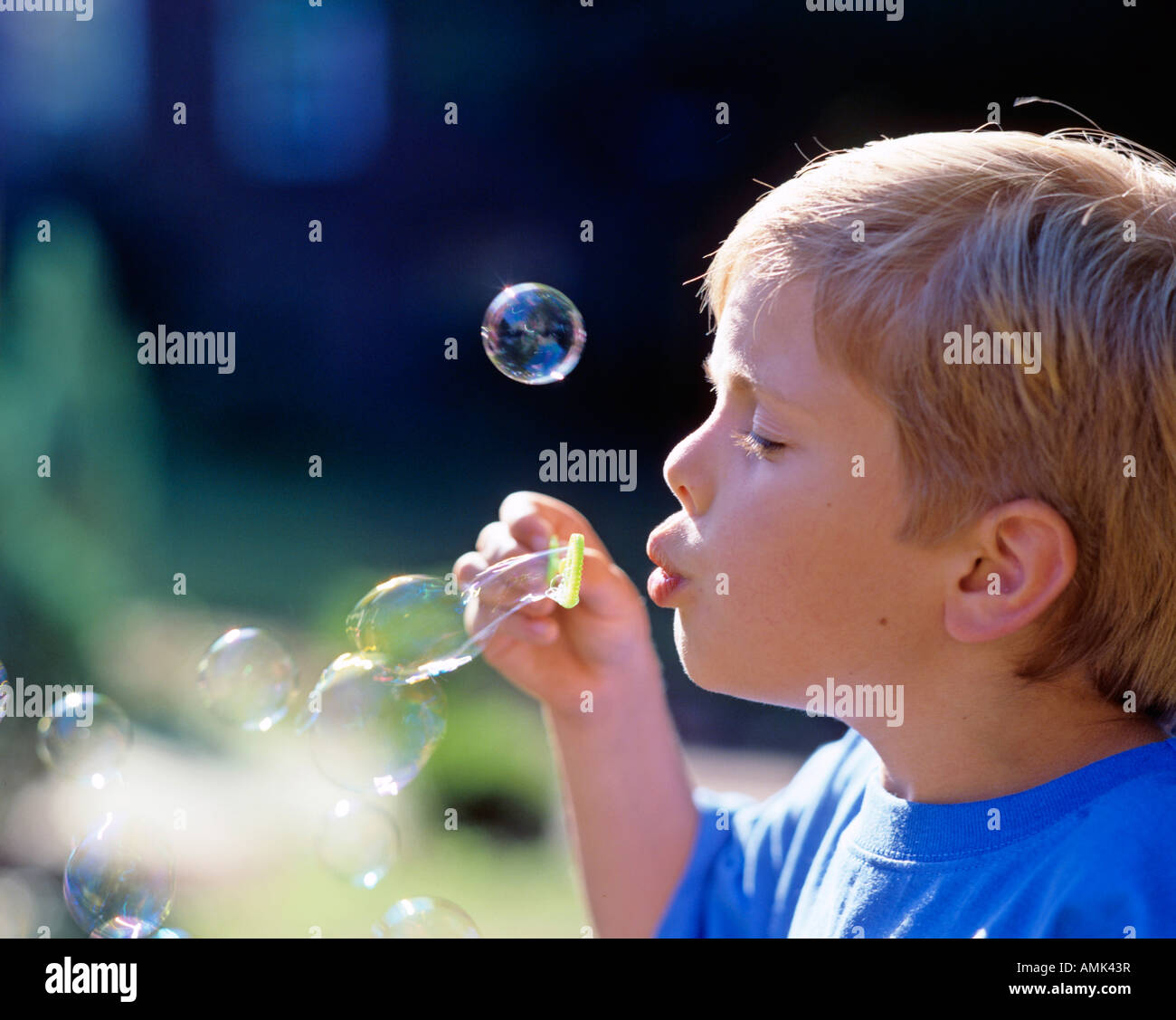 Portrait of a boy blowing bubbles side view Stock Photo - Alamy
