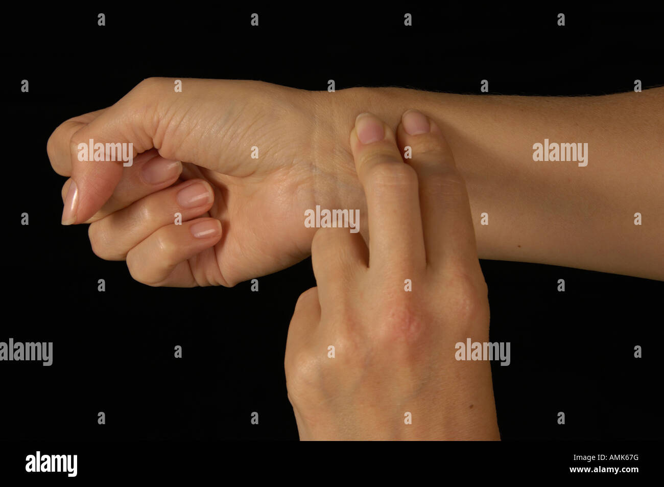 Female shown taking her own pulse isolated against a black background ...