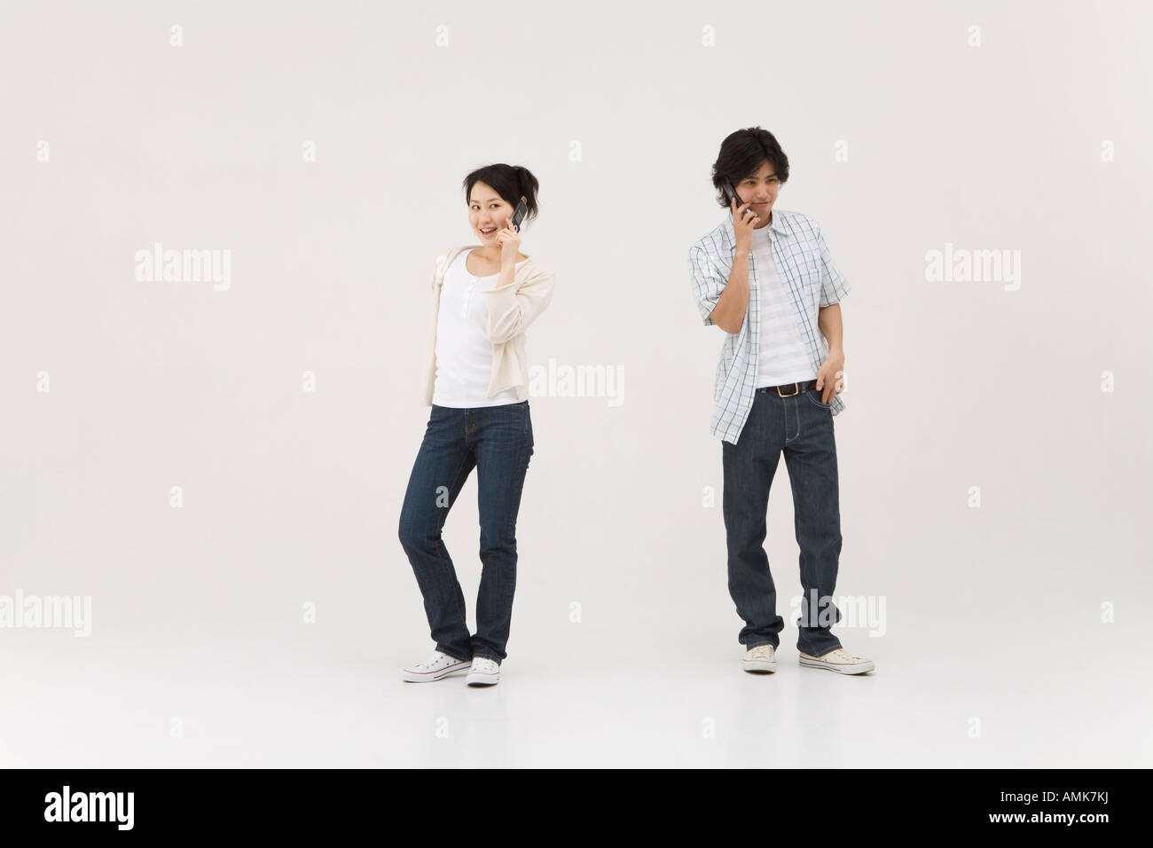 Two young people talking over mobile phones Stock Photo - Alamy