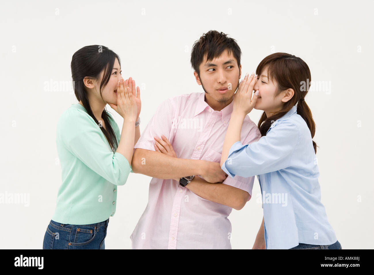 Two young women whispering to young man Stock Photo - Alamy