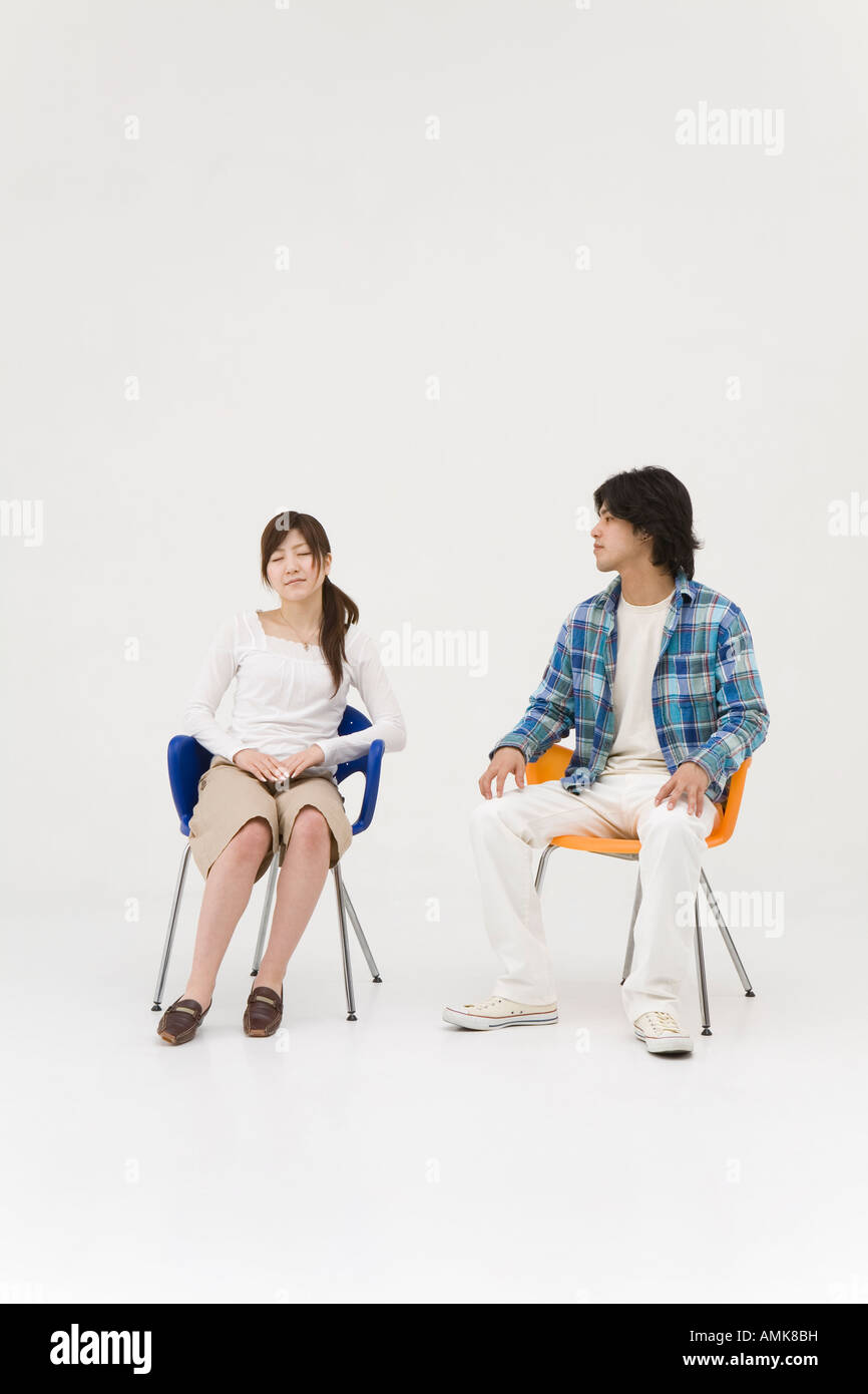 Two young people sitting in chairs Stock Photo - Alamy