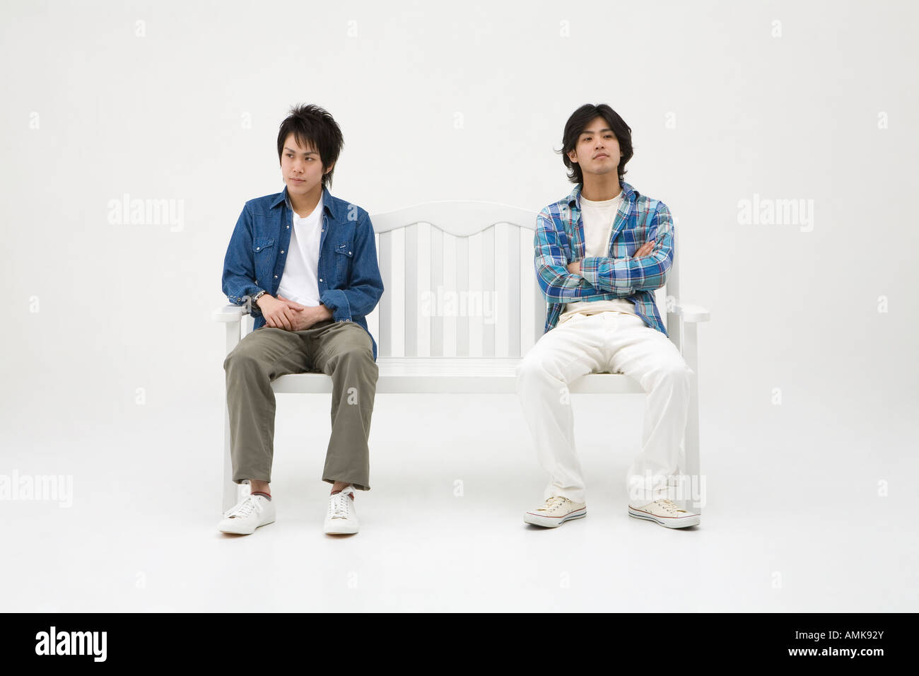 Two young men sitting on bench Stock Photo - Alamy