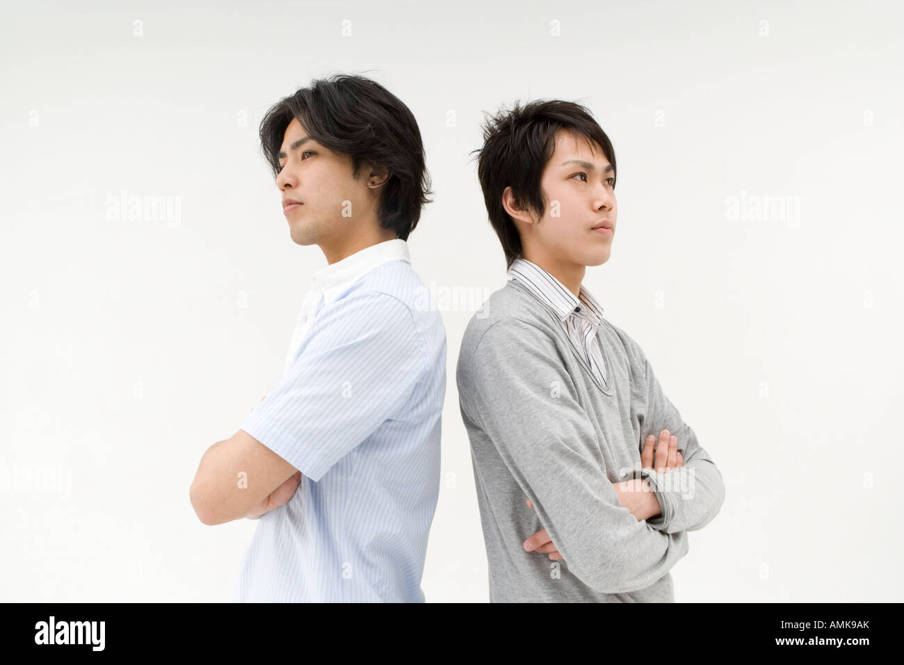 Two young men standing back to back Stock Photo - Alamy