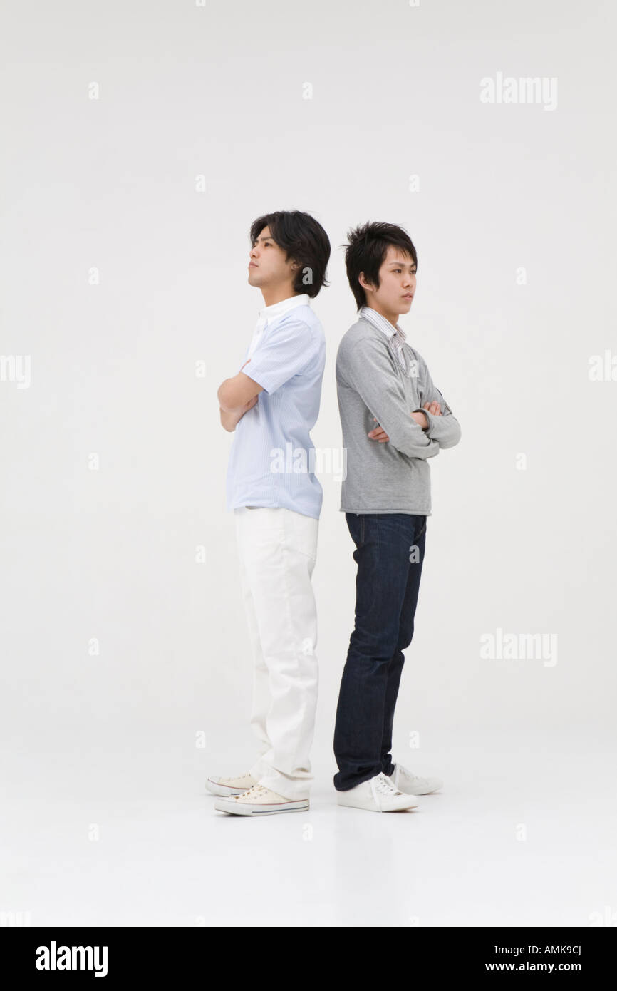 Two young men standing back to back Stock Photo - Alamy
