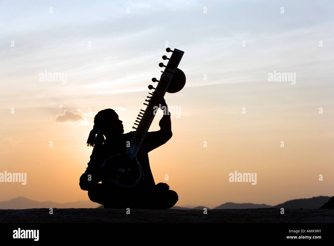 Indian man playing a sitar on rock at sunset. India Stock Photo - Alamy