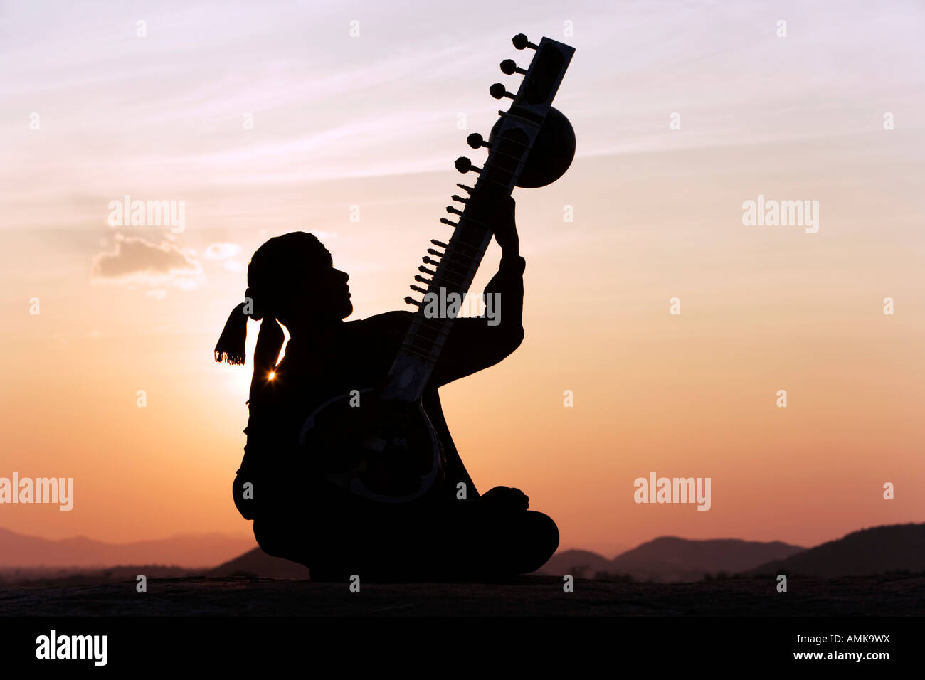 Indian man playing a sitar on rock at sunset. India Stock Photo - Alamy