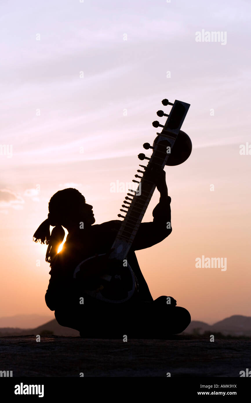 Indian man playing a sitar on rock at sunset. India Stock Photo - Alamy