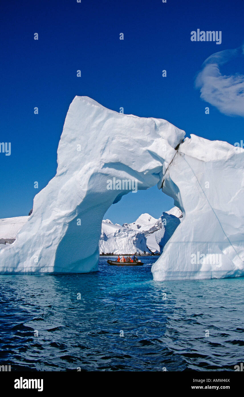 Tourists Zodiac cruising by arched iceberg near Booth Island Stock ...