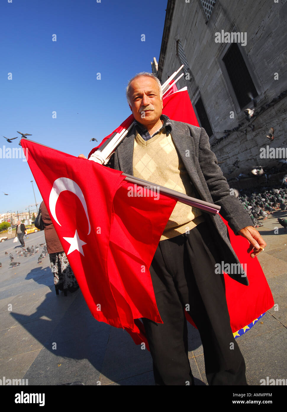 ISTANBUL, TURKEY. A man selling Turkish flags outside the Yeni Mosque ...