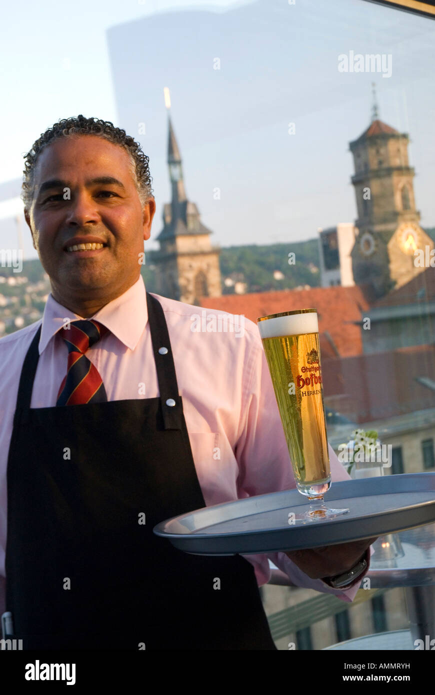 Waiter with beer in Restaurant Cube and Stiftskirche church at the back ...