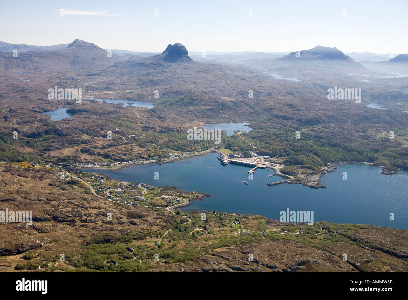 An aerial view of Lochinver with harbour visible and mountain of Canisp ...