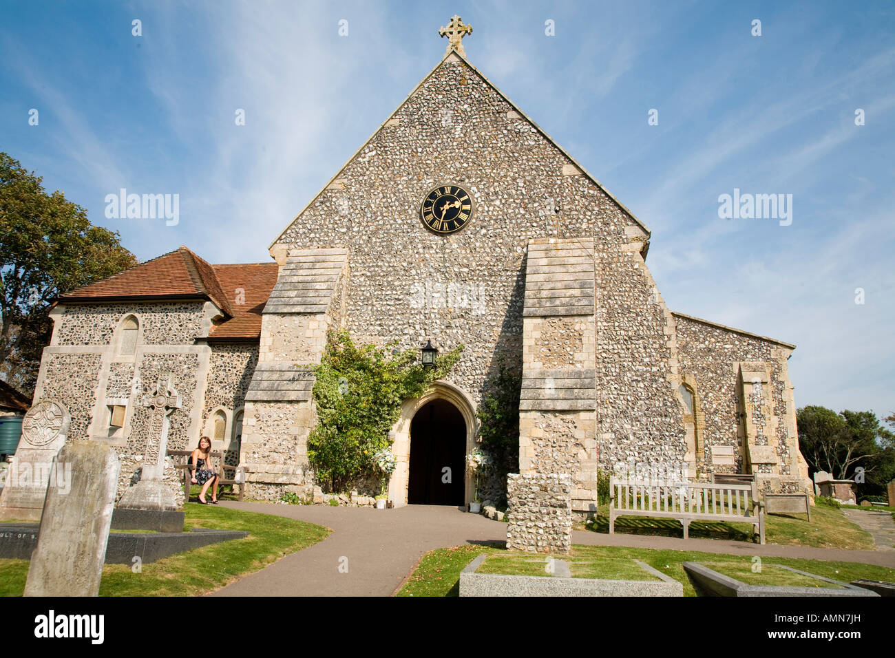 Saint Margarets Church, Rottingdean, East Sussex. A woman sits on a ...