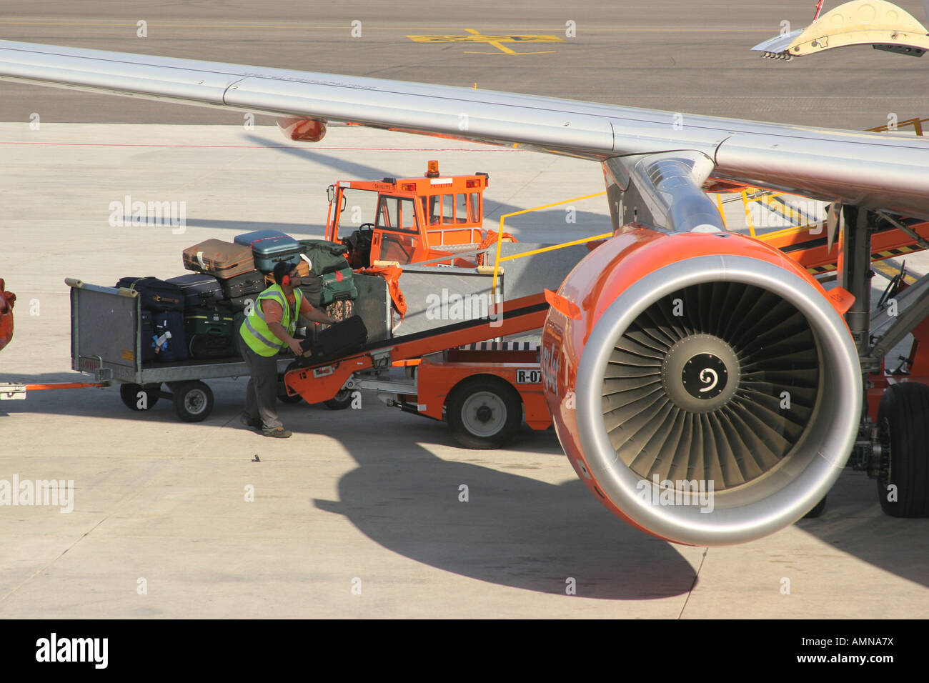 Baggage handling loading cases into jet with jet engine in foreground ...