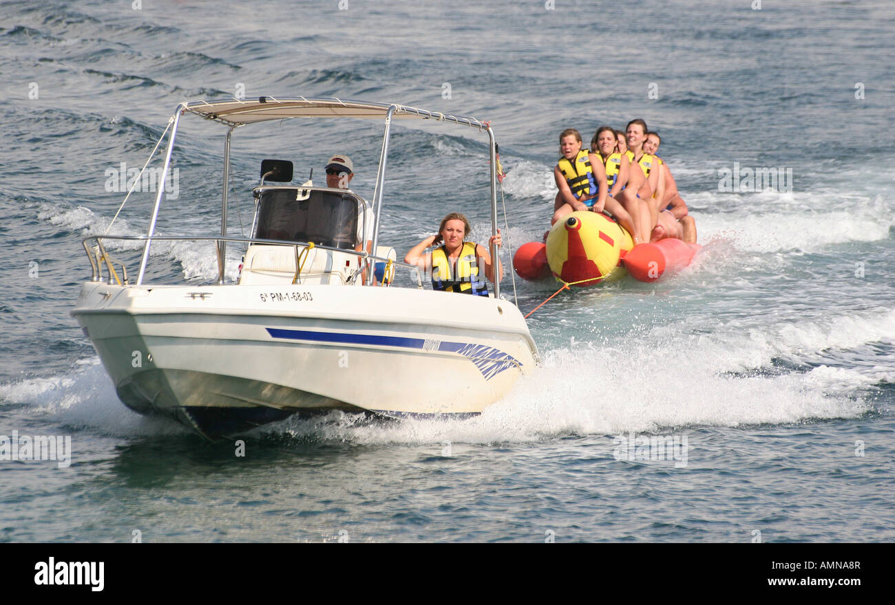 Speedboat pulling group of young people on a rubber banana boat with ...