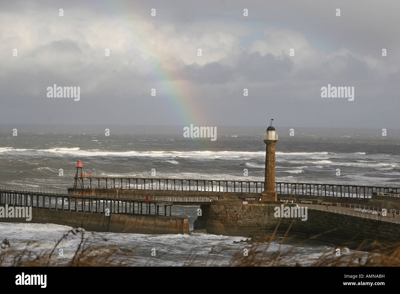 Part of a rainbow in strong wind and rain above the harbour piers at ...