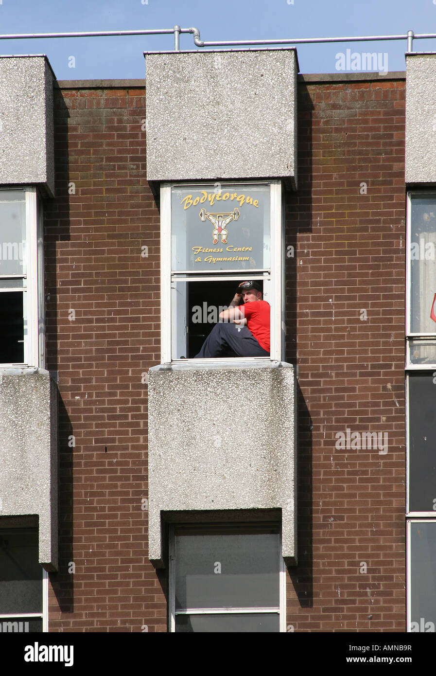 Man sitting in open window at a high level above the street putting ...