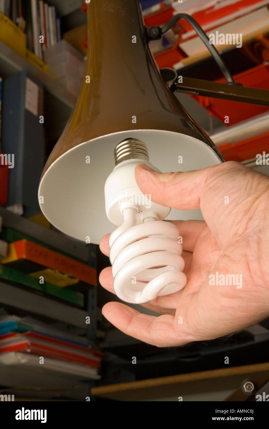 Changing to an energy efficient bulb in a desk lamp Stock Photo - Alamy