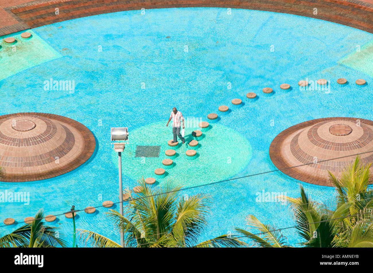 Man carefully walking on stepping stones through water pool in Durban ...