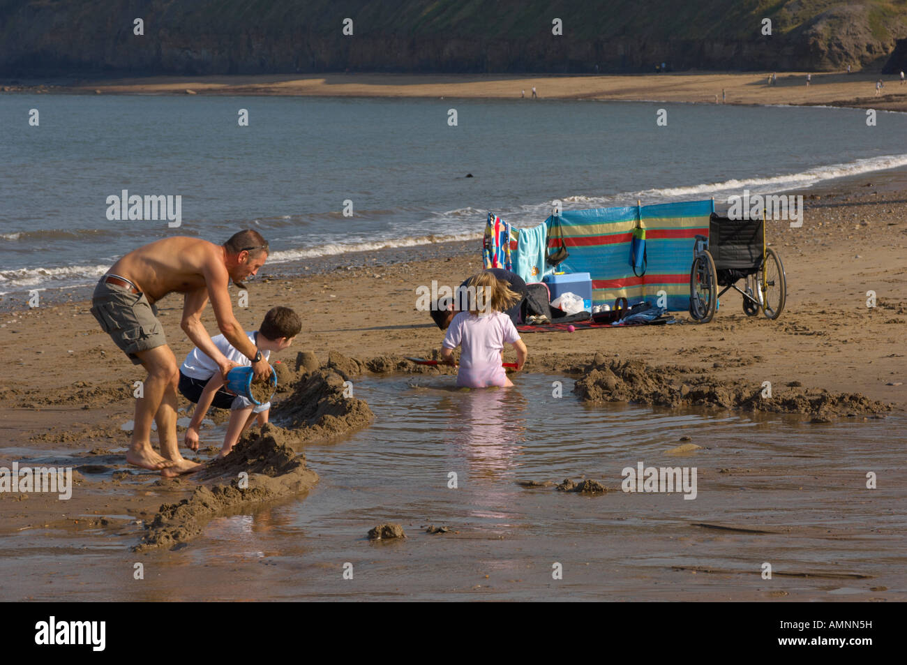 Family making sand castles on the beach. Traditional English sea side ...
