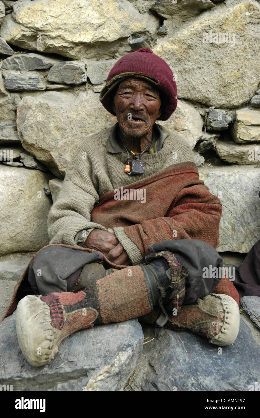 Old man wearing woolen cap and boots made of yak leather at a wall of ...