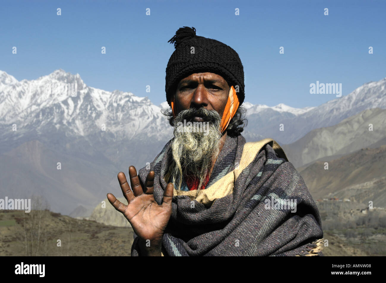 Portrait Hindu pilgrim sadhu with beard and woolen cap in front of snow ...
