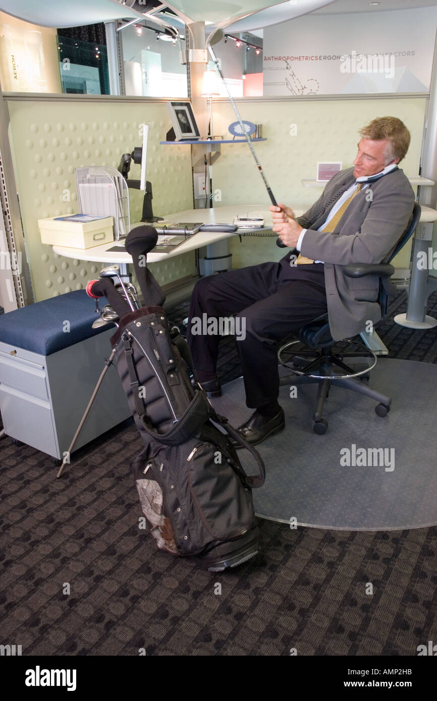 Adult businessman with golf club at desk Stock Photo - Alamy