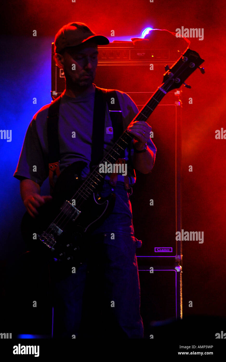 Bassist from The Saw Doctors in baseball cap performing on stage with ...