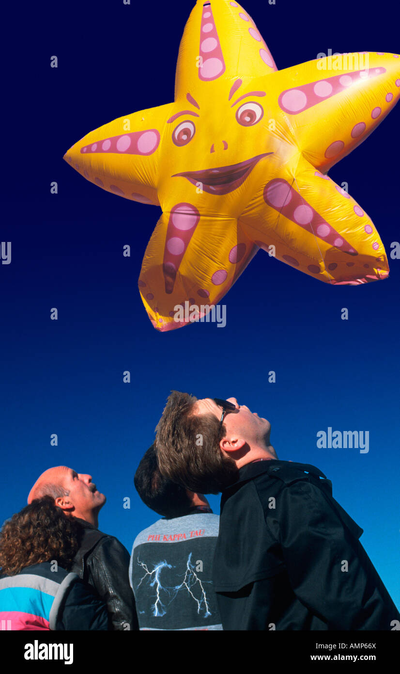 Composite image of spectators looking up at a scary yellow star-shaped ...
