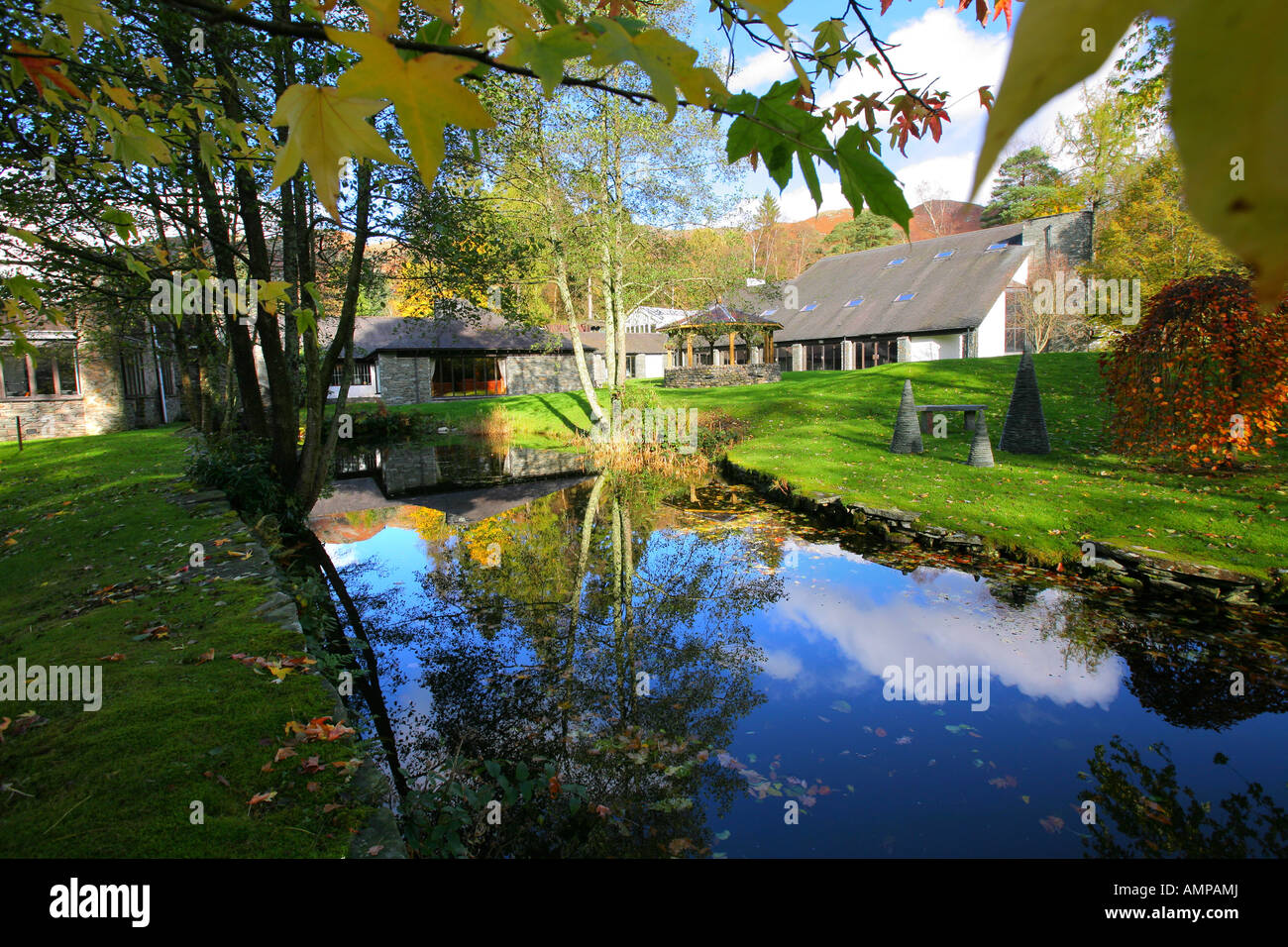 Wide stream with grassy banks, framed and lined with trees with farm ...