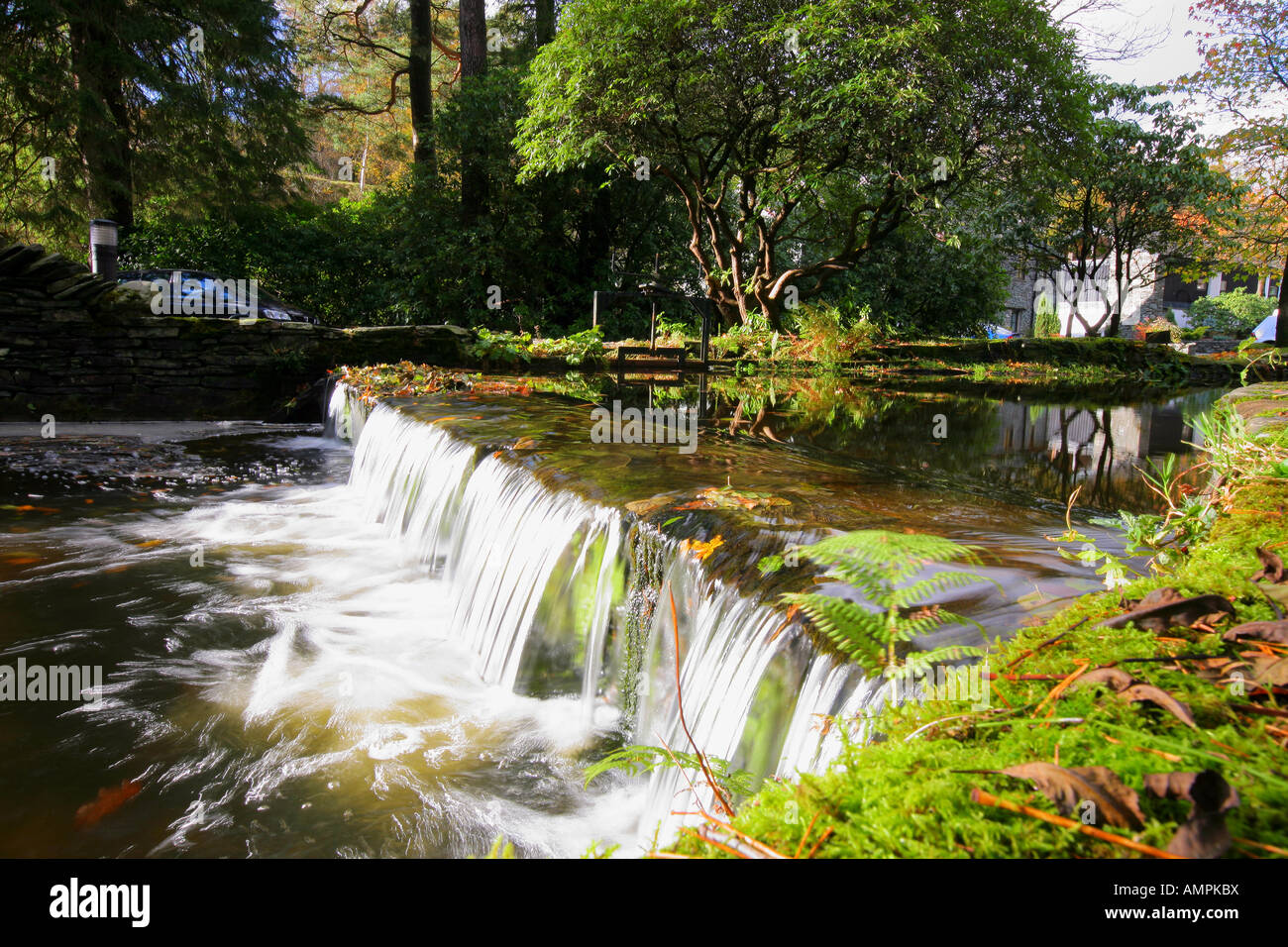Weir in fast flowing stream lines with trees in Lake District Stock ...