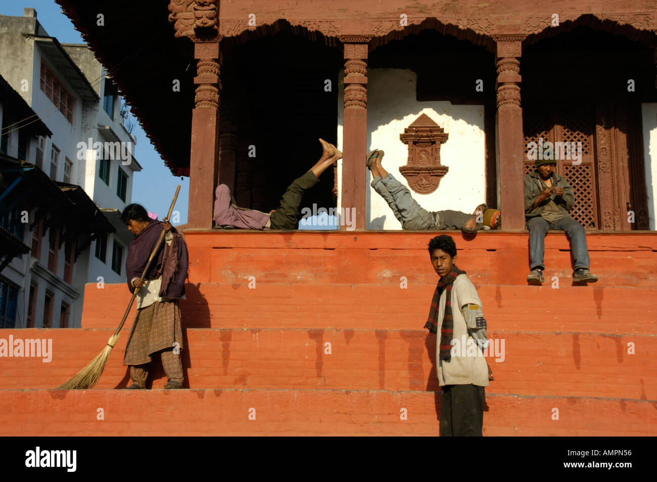 Men at rest holding their legs high at a temple woman brushes with a ...