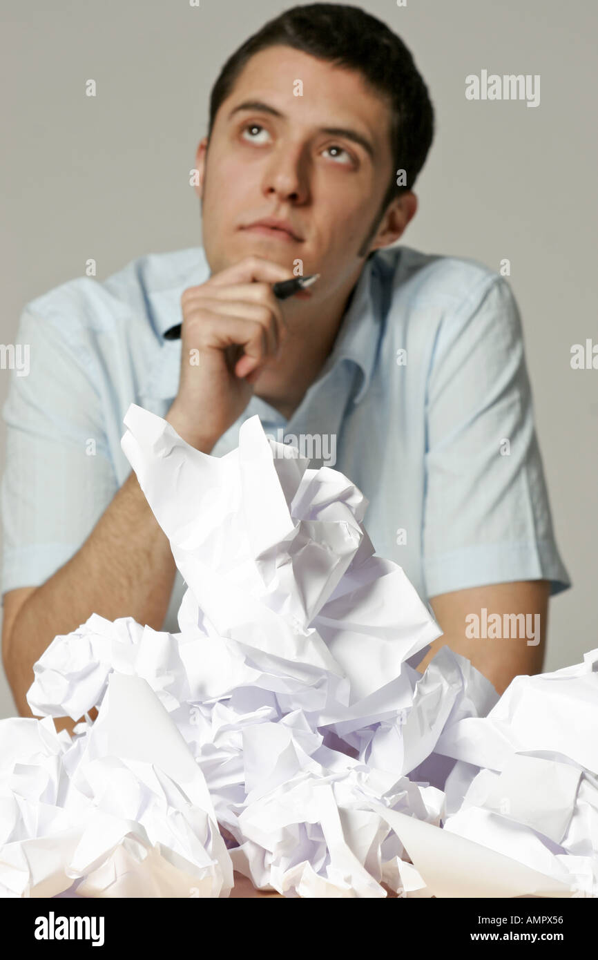 Young man sitting at desk with crumpled paper Stock Photo - Alamy