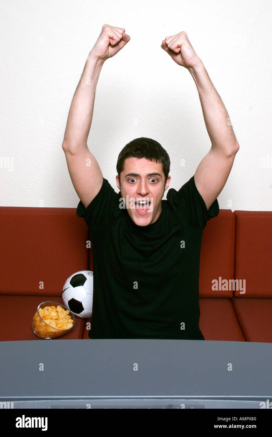Young man watching TV, punching air Stock Photo - Alamy