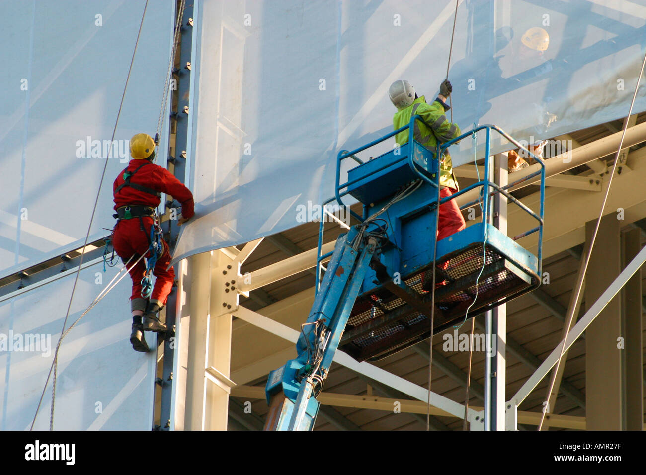 Abseilers installing fabric screens on industrial building Stock Photo ...