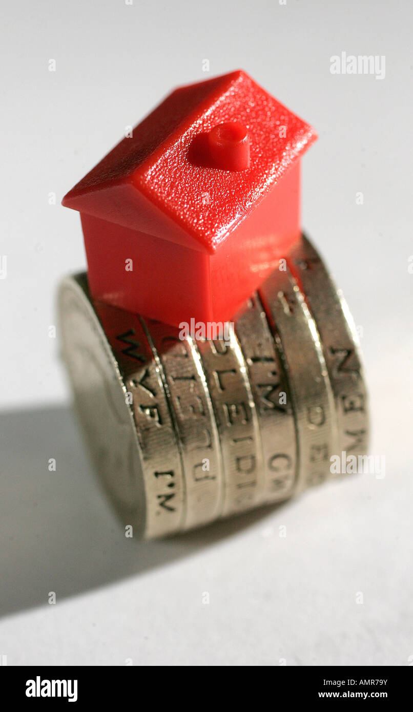 A monopoly house sits ontop of a pile of pound coins Stock Photo - Alamy