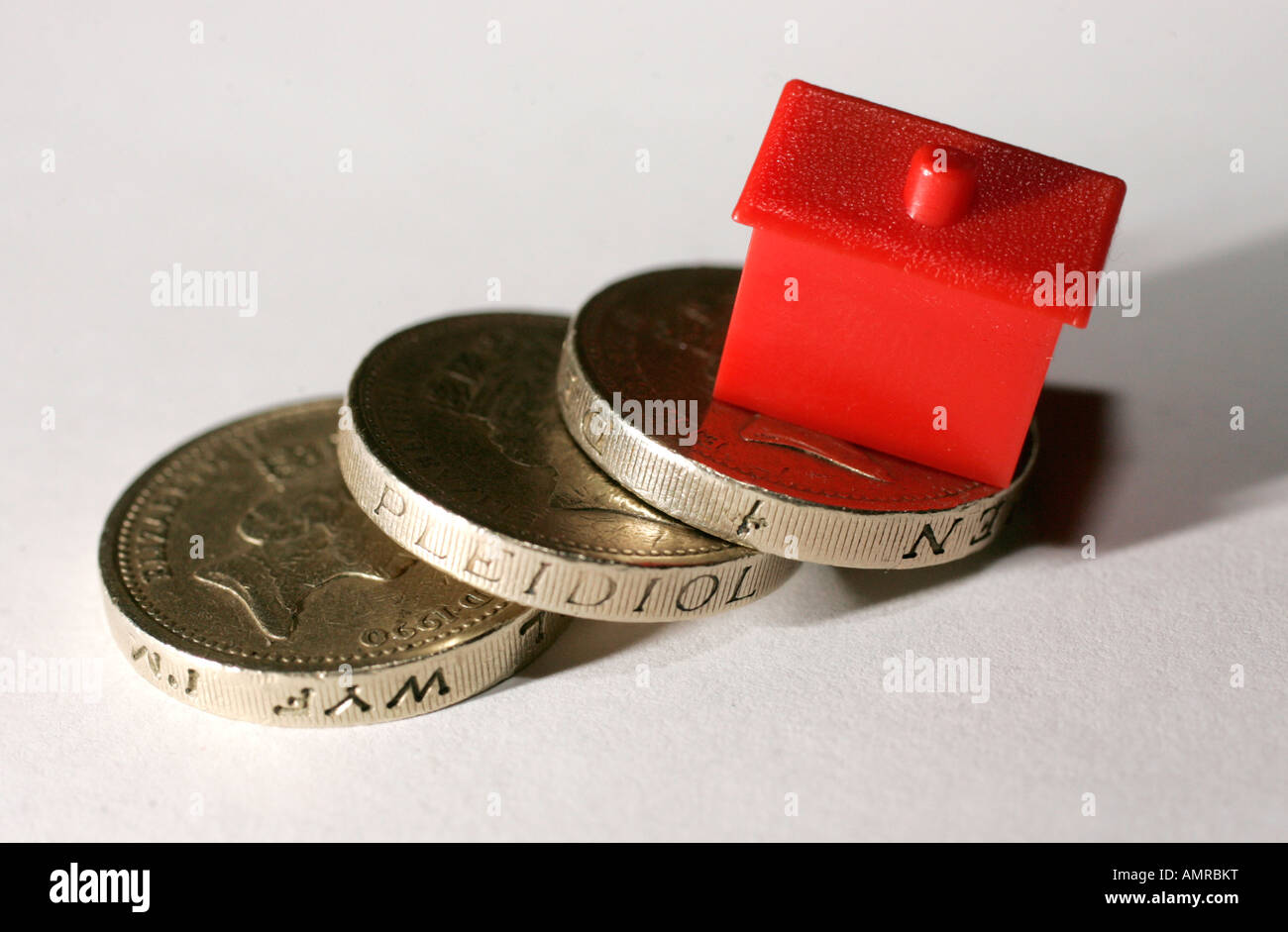 A monopoly house sits ontop of a pile of pound coins Stock Photo - Alamy