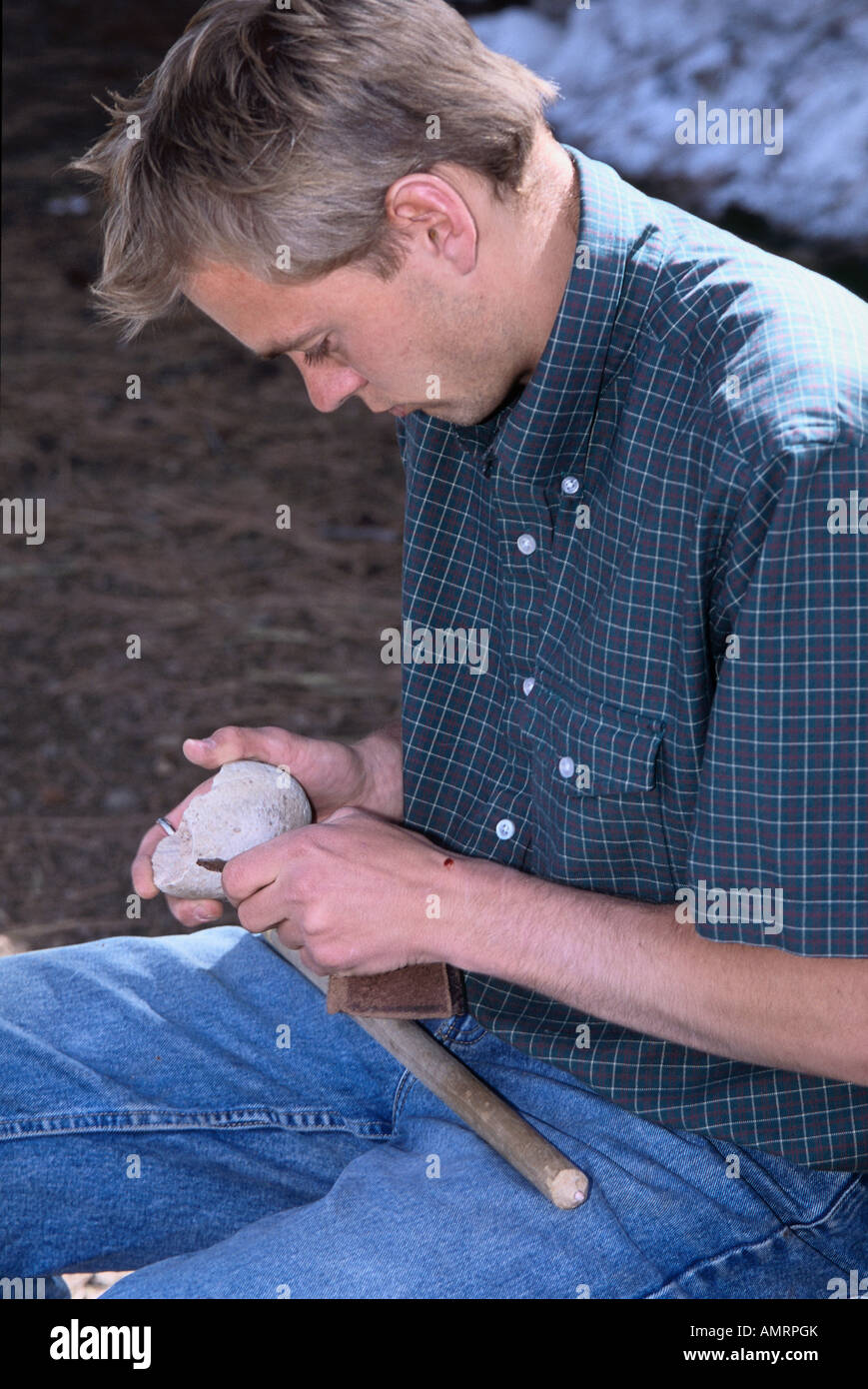 Flintknapping expert Randy Haas shapes an arrowhead with a large stone ...