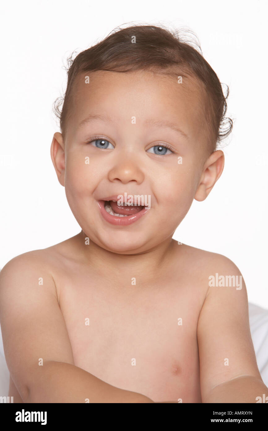 A brunette baby sits up and smiles against a white background Stock ...