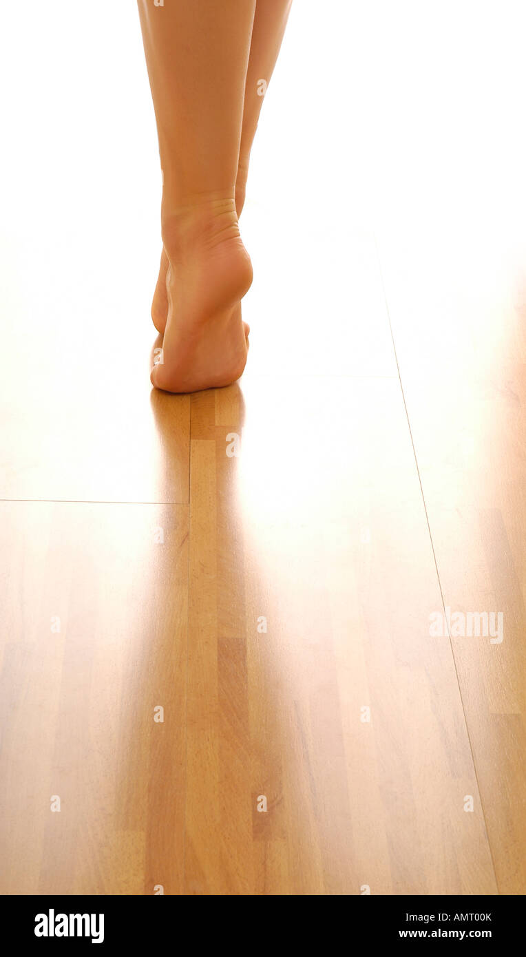 Closeup girl's of feet, ankles and legs from back on polished wooden ...