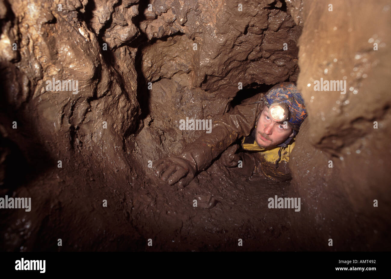 A caver in a muddy passage in a cave in the Brecon Beacons South Wales ...