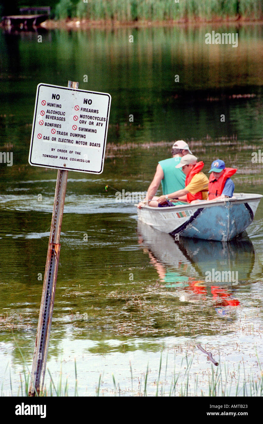 Sign with many no s posted on inland recreational lake and family on a ...